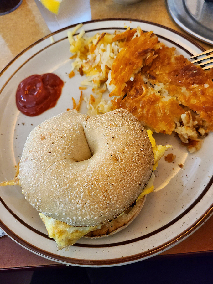 Breakfast sandwich architecture at its finest &ndash; the structural integrity of that bagel deserves an engineering award, while the hash browns bring the crispy comfort.