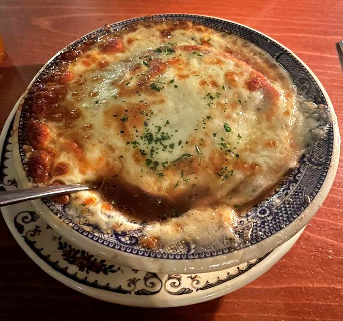Behold the French onion soup that launched a thousand spoons! Melted cheese stretches skyward like revolutionary flags, while savory broth awaits below.
