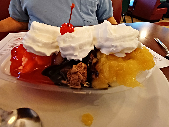 Three distinct ice cream flavors crowned with whipped cream mountains and a cherry sentinel&mdash;dessert architecture at its finest.
