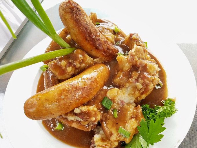 Bangers and mash swimming in rich onion gravy &ndash; comfort food that hugs you from the inside like a warm British cardigan.