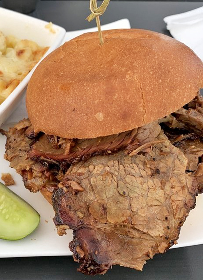 This isn't just a sandwich; it's a skyscraper of oak-smoked brisket that requires both hands, several napkins, and absolutely zero shame.