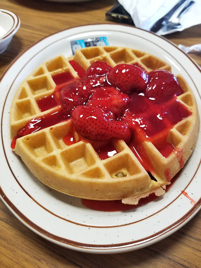 A Belgian waffle drowning in strawberry syrup &ndash; the kind of sweet disaster your doctor warned you about.