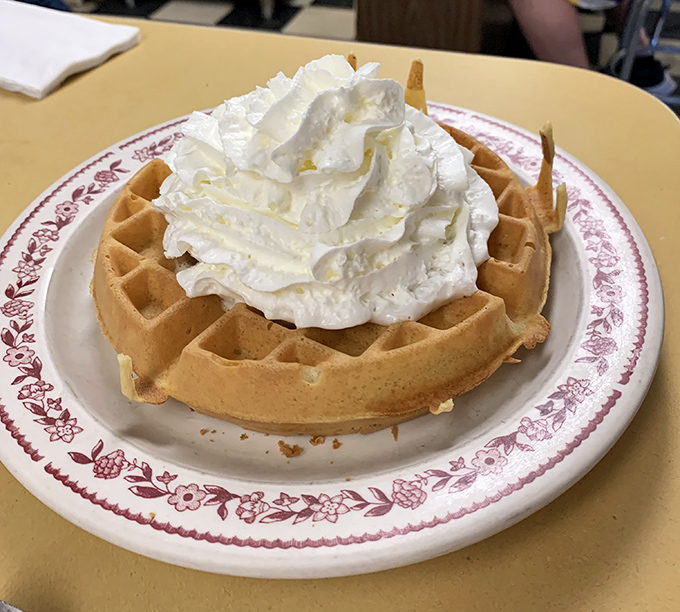 This Belgian waffle wears whipped cream like a crown, ruling over the breakfast kingdom with fluffy authority.