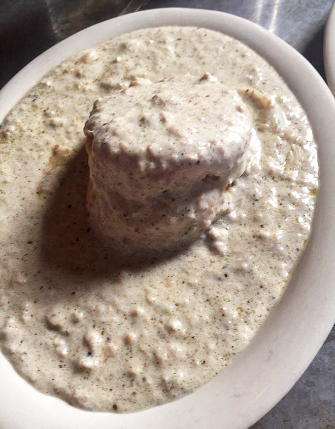 That biscuit drowning in sausage gravy represents everything beautiful about Southern comfort food done absolutely right.