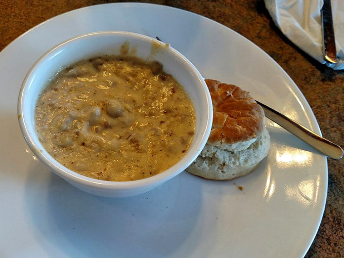 A bowl of creamy sausage gravy with a fresh-baked biscuit standing by. Southern comfort that migrated north and found a happy home.