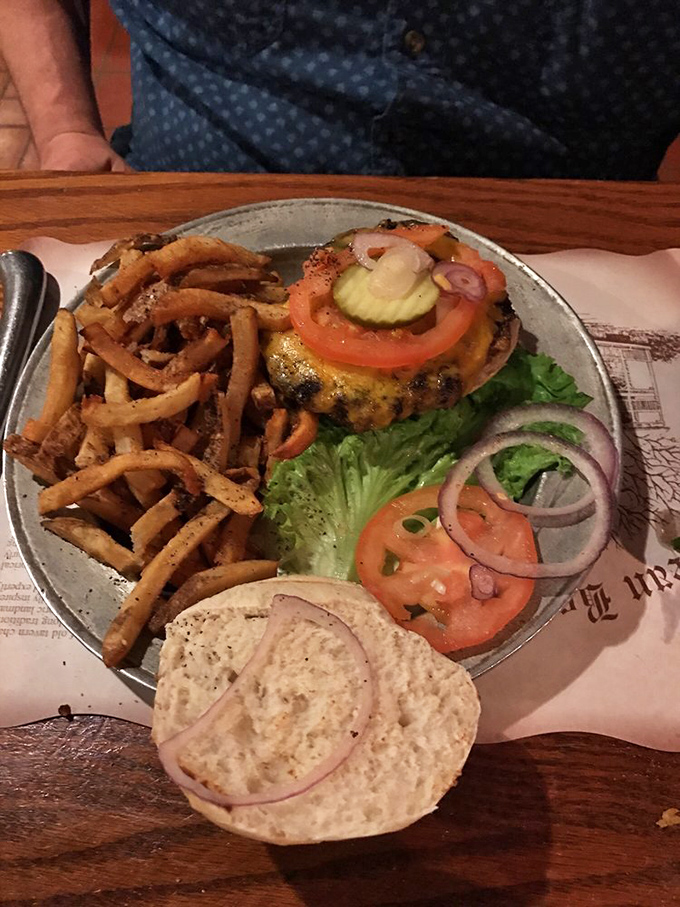 A burger that requires both hands and a strategy, flanked by fries so perfectly golden they deserve their own Fort Knox.