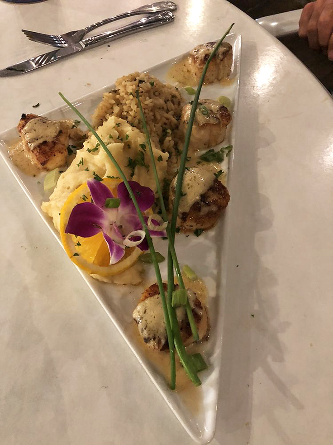 Blackened scallops nestled against rice and garnished with fresh herbs &ndash; proof that simple ingredients can create culinary poetry.