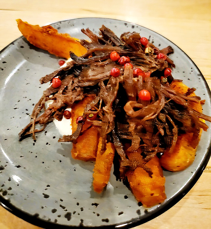 Slow-braised beef sprawled across hand-cut fries like it owns the place. Those bright pomegranate seeds add pops of flavor that'll make your taste buds dance.