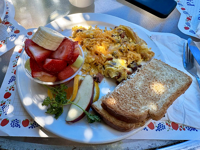 A breakfast symphony on a plate: scrambled eggs, fresh fruit, and toast creating the kind of harmony that makes morning people out of night owls.