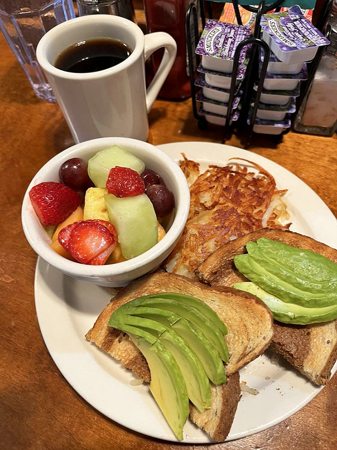 Avocado toast that doesn't require a second mortgage, served with fresh fruit and hash browns. California breakfast perfection.