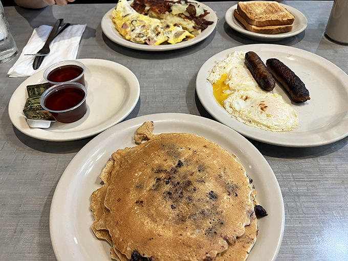 Breakfast symphony: golden pancakes, perfectly fried eggs, and sausages that snap with each bite. Morning glory on pristine white plates.