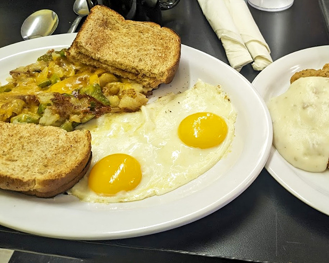 The holy trinity of breakfast perfection: sunny-side-up eggs with yolks like liquid gold, crispy potatoes, and toast standing by for yolk-sopping duty.