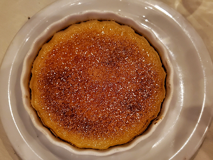 The cr&egrave;me br&ucirc;l&eacute;e's caramelized top shatters with satisfying precision, revealing a silky custard that would make a French pastry chef weep with joy.