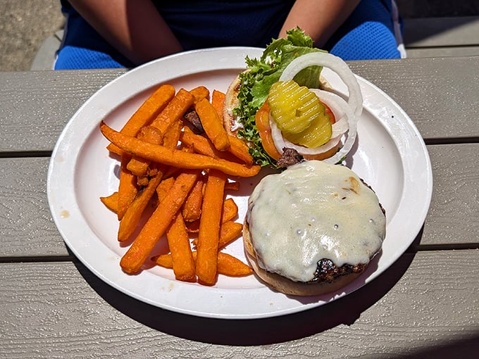A burger that demands both hands and your full attention, served with sweet potato fries that could make regular potatoes jealous.