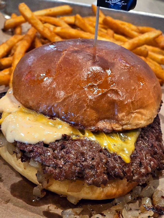 Behold the burger that launched a thousand napkins! Melted cheese cascades over a smoky patty like a yellow waterfall of deliciousness.