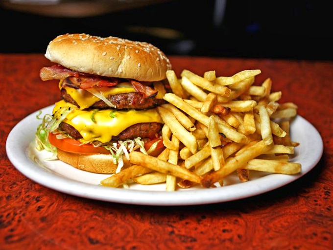 The burger arrives like a beautiful, beefy monument to excess. Those golden fries aren't a side dish—they're co-stars in this delicious production.