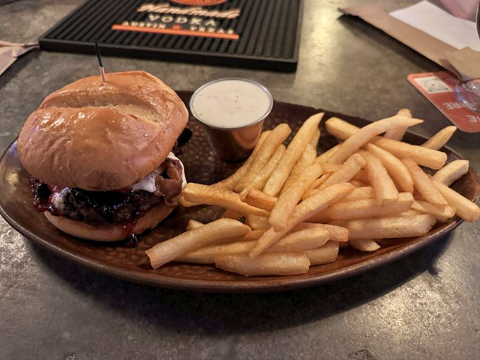 The burger arrives like a champion on its throne, juicy and magnificent, with fries standing at attention like loyal subjects.