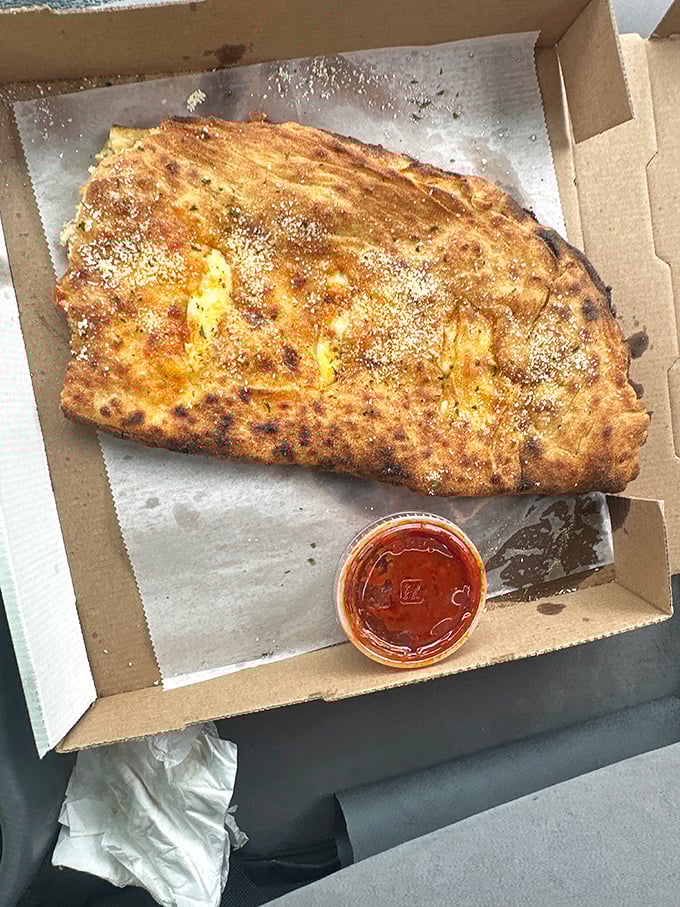The calzone: pizza's mysterious folded cousin. This golden-brown beauty with its side of marinara is what carb dreams are made of.