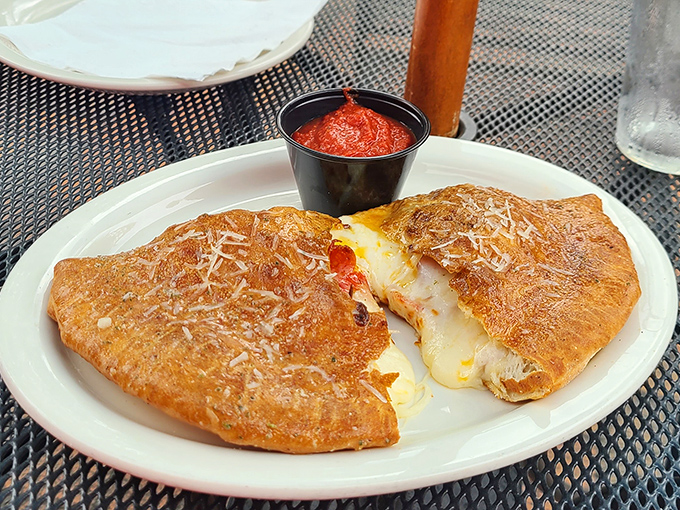 The calzone arrives like a golden treasure chest, its crisp exterior giving way to a molten interior that would make even the most disciplined diner weak-kneed.