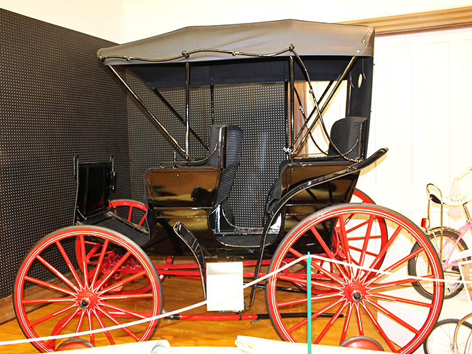 Not quite a bicycle, not quite a carriage&mdash;this canopy-topped Surrey with its bright red wheels represents the elegant transition between horse-drawn and human-powered transportation.