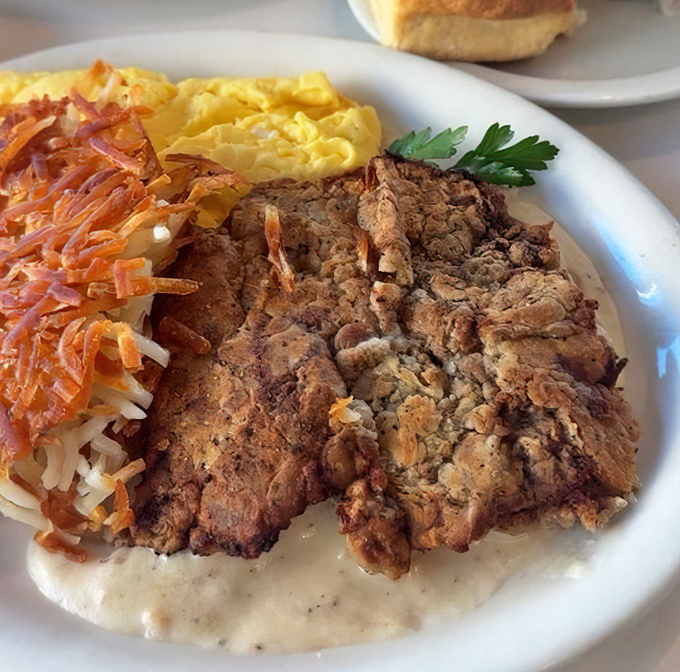 Chicken fried steak arrives golden and crispy, accompanied by hash browns that could make angels weep.