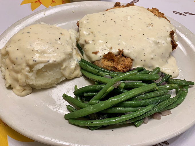 Chicken fried steak and a biscuit, both swimming in gravy like synchronized comfort food athletes competing for your affection.
