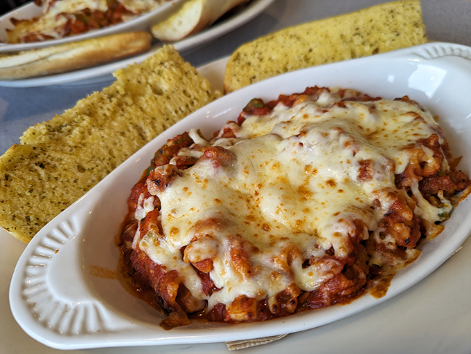 Bubbling cheese blankets this hearty chicken parmesan while garlic bread stands by, ready for the inevitable sauce-sopping mission. A comfort food masterpiece.