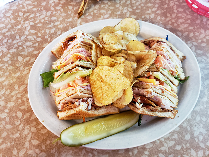 A club sandwich that towers like the Mackinac Bridge, layered with care and flanked by house-made chips. That pickle means business. 