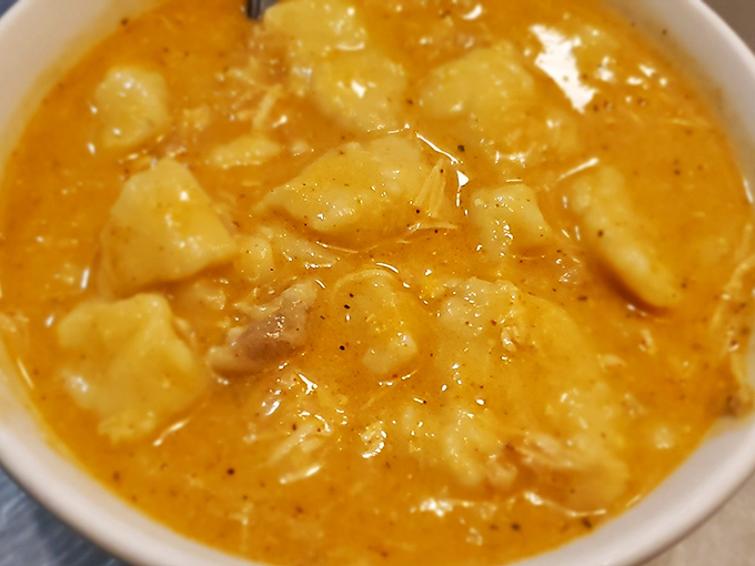 Chicken and dumplings swimming in golden broth—proof that soup isn't just a starter but sometimes the whole point of leaving your house.