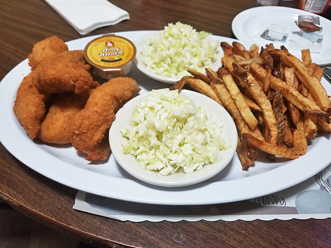 Chicken tenders that actually deserve the name "tender," flanked by twin mounds of fresh coleslaw. This plate knows exactly what comfort food should be.