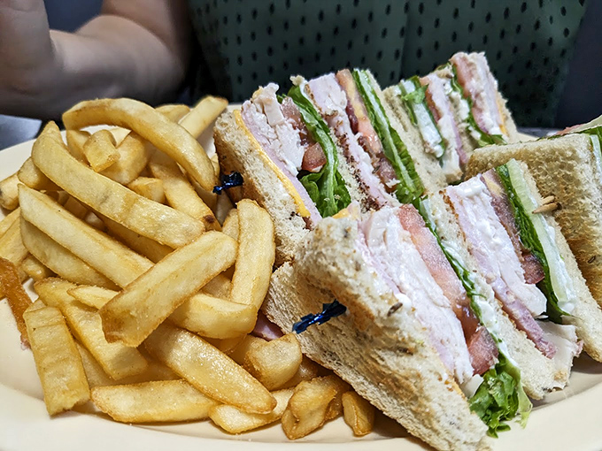 This club sandwich isn't just stacked with layers&mdash;it's stacked with tradition, served with a side of golden fries that crackle with each bite.