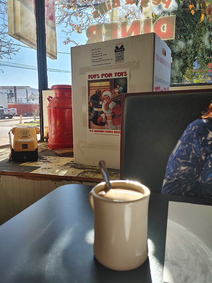 That classic white mug isn't just holding coffee&mdash;it's cradling liquid optimism while Toys for Tots reminds you this place has heart.