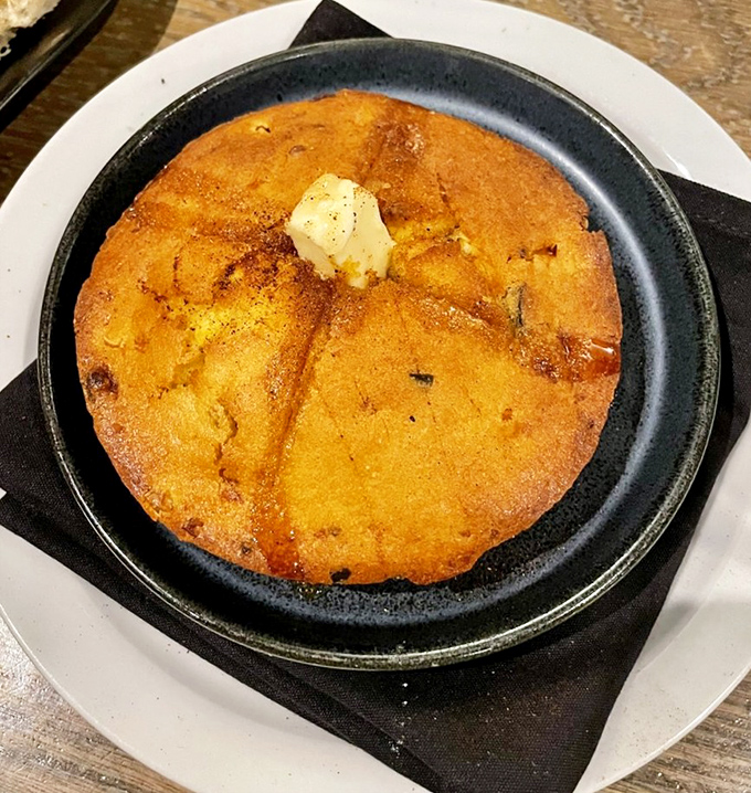 Golden cornbread that would make your grandmother simultaneously proud and jealous, topped with a pat of butter slowly melting into submission.