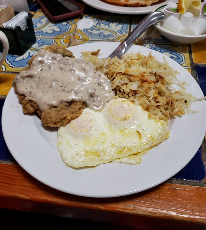Country fried steak smothered in peppery gravy alongside eggs and hash browns—the breakfast equivalent of a warm hug from your favorite aunt.