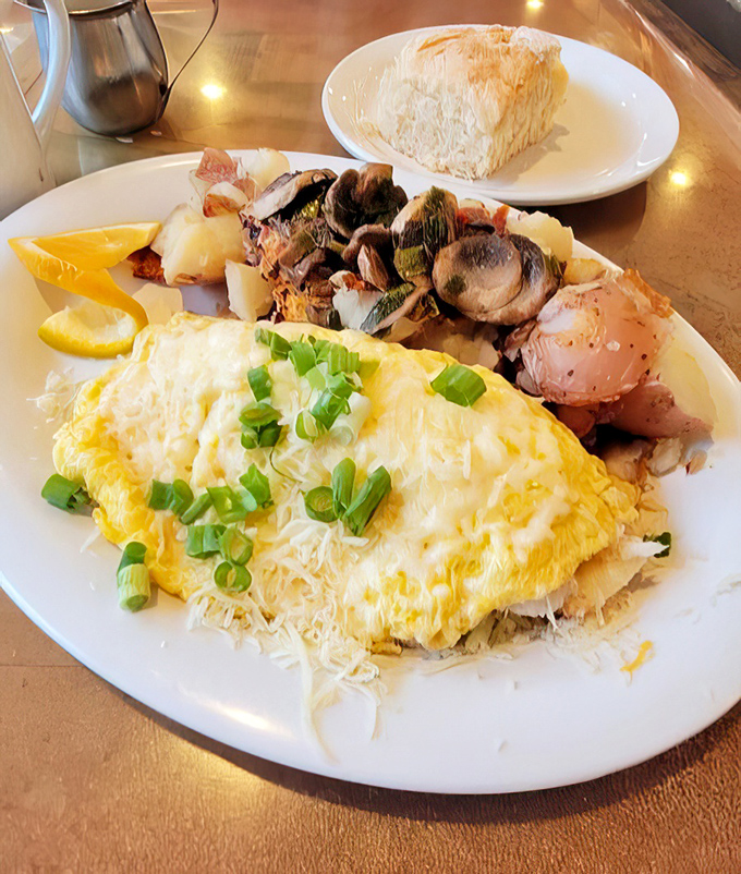 Breakfast reaches new heights with this fluffy omelet crowned with melted cheese and green onions, accompanied by perfectly roasted potatoes and mushrooms.
