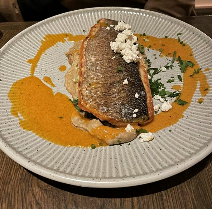 The crispy branzino arrives like a work of art &ndash; crisp skin, tender flesh, and a sauce so good you'll consider drinking it straight.