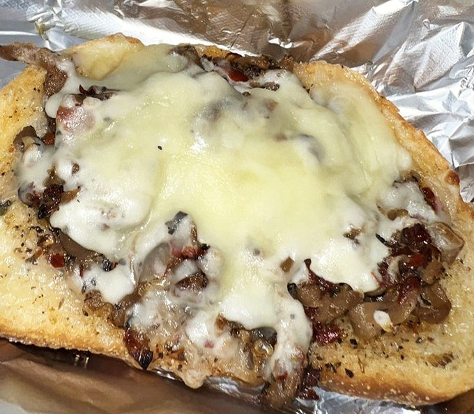 This open-faced sandwich isn't just topped with cheese &ndash; it's wearing a magnificent melted crown. Comfort food royalty served on humble aluminum foil.