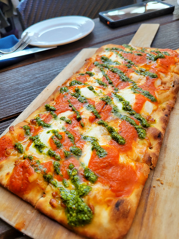 Pizza gets a glow-up with this flatbread masterpiece. That pesto drizzle is performing culinary ballet across those perfect tomatoes.
