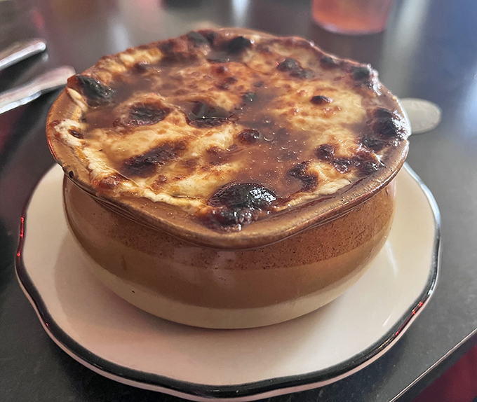 This isn't just French onion soup&mdash;it's a geological wonder with a molten cheese cap that requires strategic drilling to reach the savory broth below.