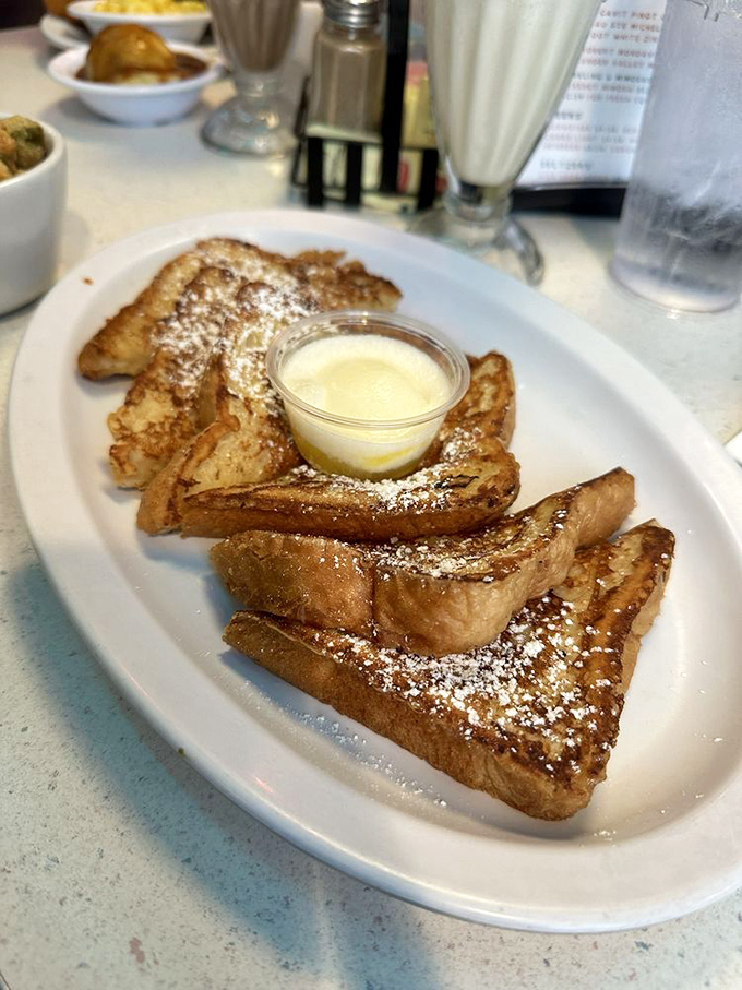 French toast that's achieved the impossible balance: crispy edges, custardy centers, and enough powdered sugar to make your dentist wince approvingly.