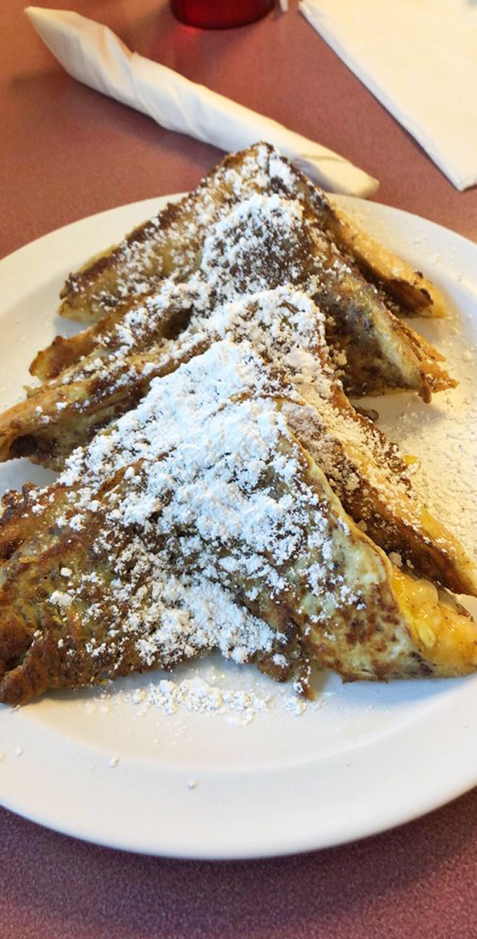 French toast that's crossed the line from breakfast to dessert, wearing its powdered sugar crown with the confidence of food that knows it's irresistible.
