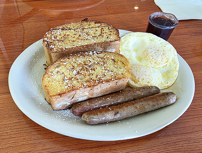 French toast dusted with powdered sugar alongside perfectly browned sausage links. The kind of plate that makes you forget your phone exists for at least twenty blissful minutes.