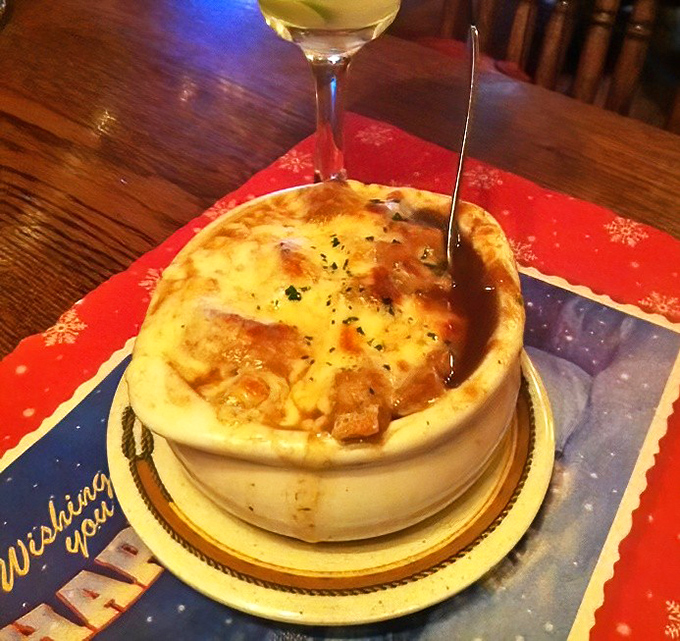 French onion soup arrives bubbling hot with cheese stretching like lasso ropes across this comfort food masterpiece.