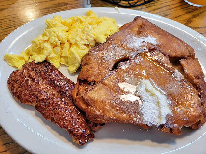 Breakfast alchemy at its finest: French toast dusted with powdered sugar alongside eggs and sausage that would make hitting the snooze button criminal.