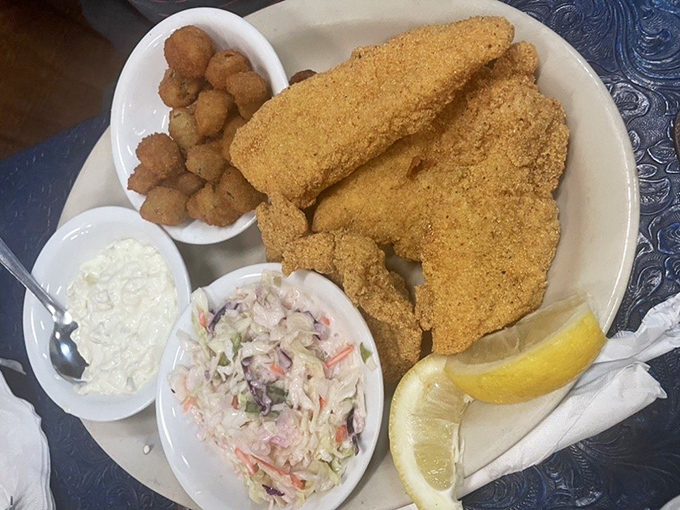 Golden-crusted catfish that tastes like it was swimming this morning, accompanied by hush puppies and coleslaw that know their supporting roles perfectly.