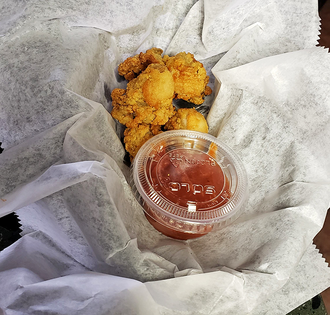 Golden-fried oysters nestled in paper with a side of cocktail sauce &ndash; proof that simplicity, when done right, is the highest form of culinary art.