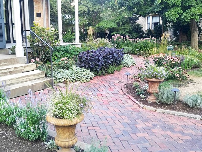 The brick pathway through meticulously maintained gardens offers a glimpse into Victorian outdoor aesthetics, where nature was beautiful but firmly controlled.