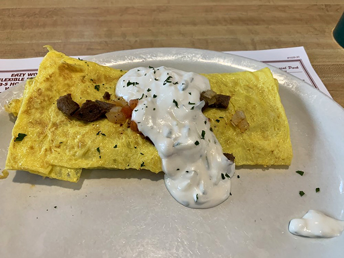 The Greek omelet arrives like a yellow canvas painted with savory ingredients and crowned with a dollop of creamy sauce. Breakfast artistry!