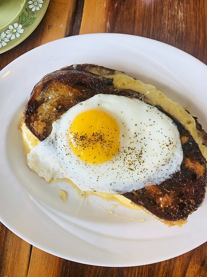 A sunny-side-up egg crowns this dish like a golden halo, transforming humble toast into a breakfast masterpiece worthy of morning worship.