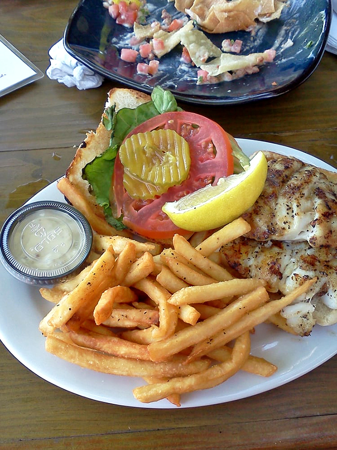 Behold the legendary grouper sandwich in its natural habitat—perfectly blackened, nestled on a brioche throne, surrounded by golden fry sentinels.